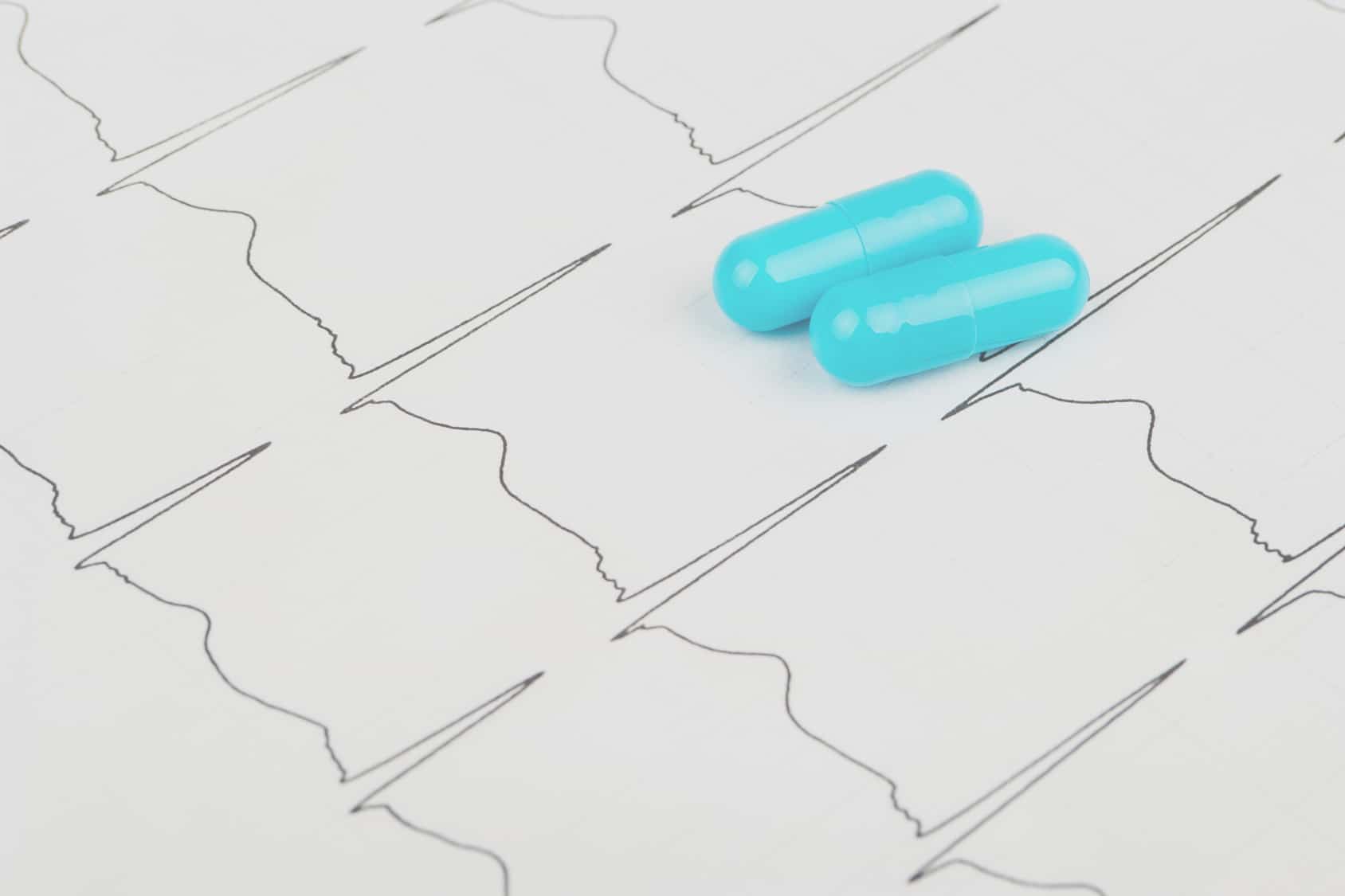 Cardiogram with the rhythm of the heartbeat and the two blue capsules ...
